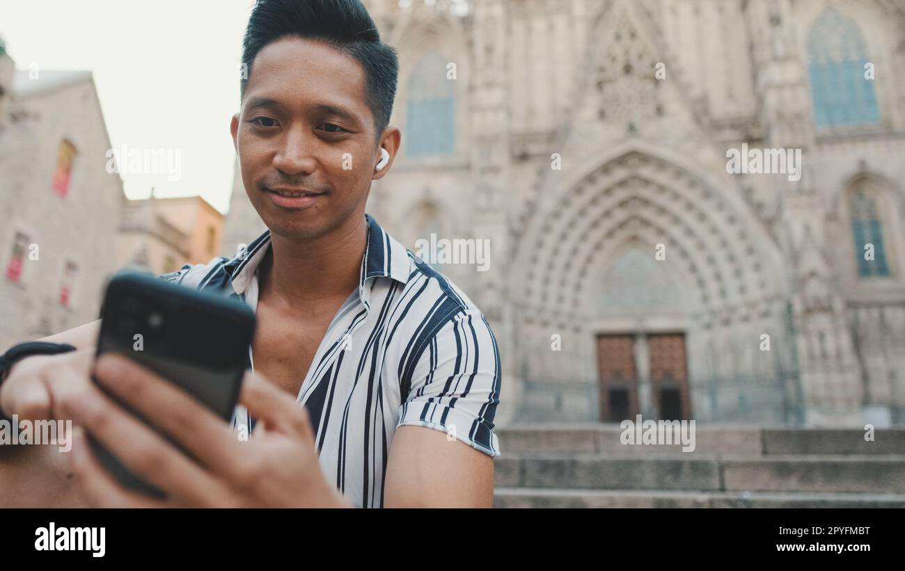 Young man tourist on steps uses mobile phone while sitting on landmarks ...