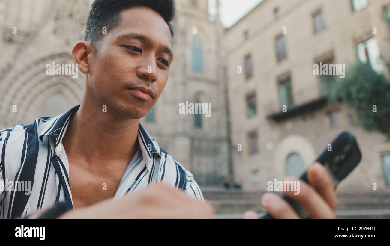 Young man tourist on steps uses mobile phone while sitting on landmarks ...