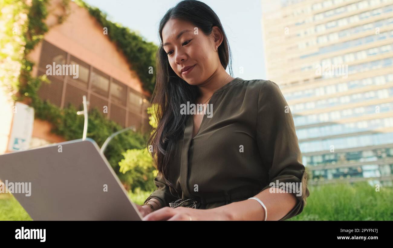 Young girl uses laptop pc outside on modern buildings background Stock ...