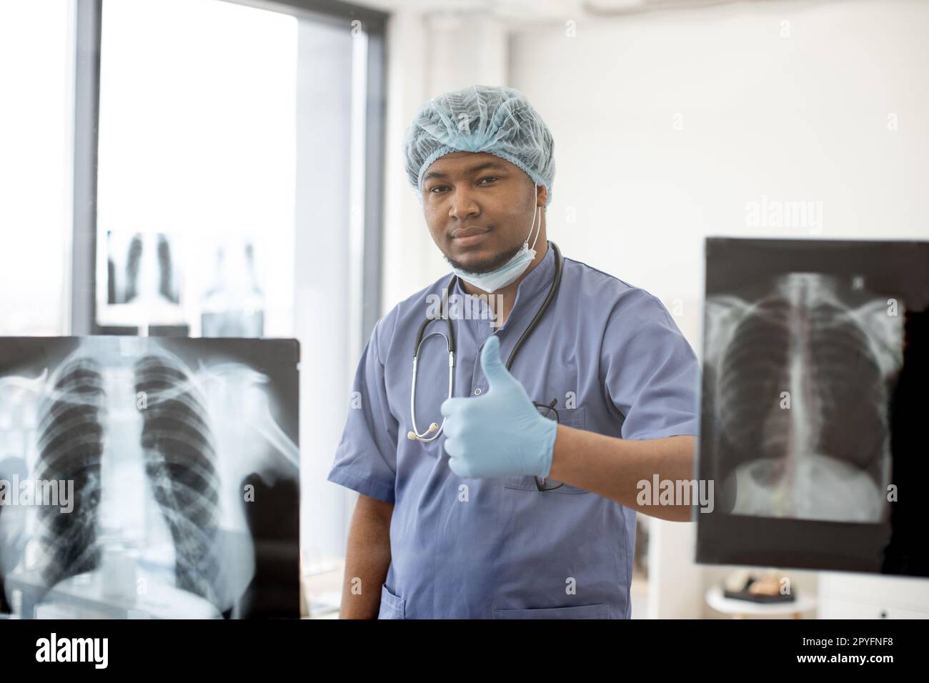 Friendly multiracial male in scrub top and latex gloves giving thumb-up ...