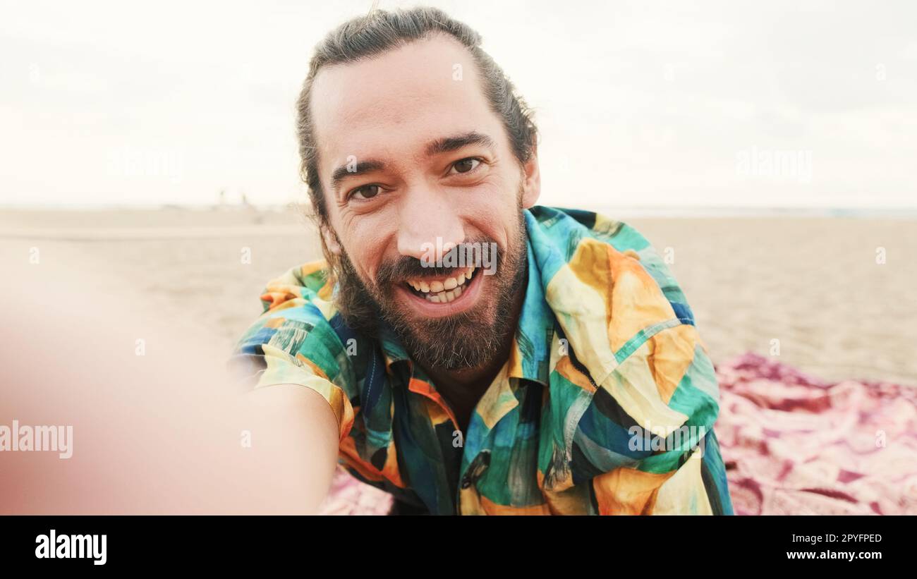 Young happy man lies talking by video call on the beach Stock Photo - Alamy