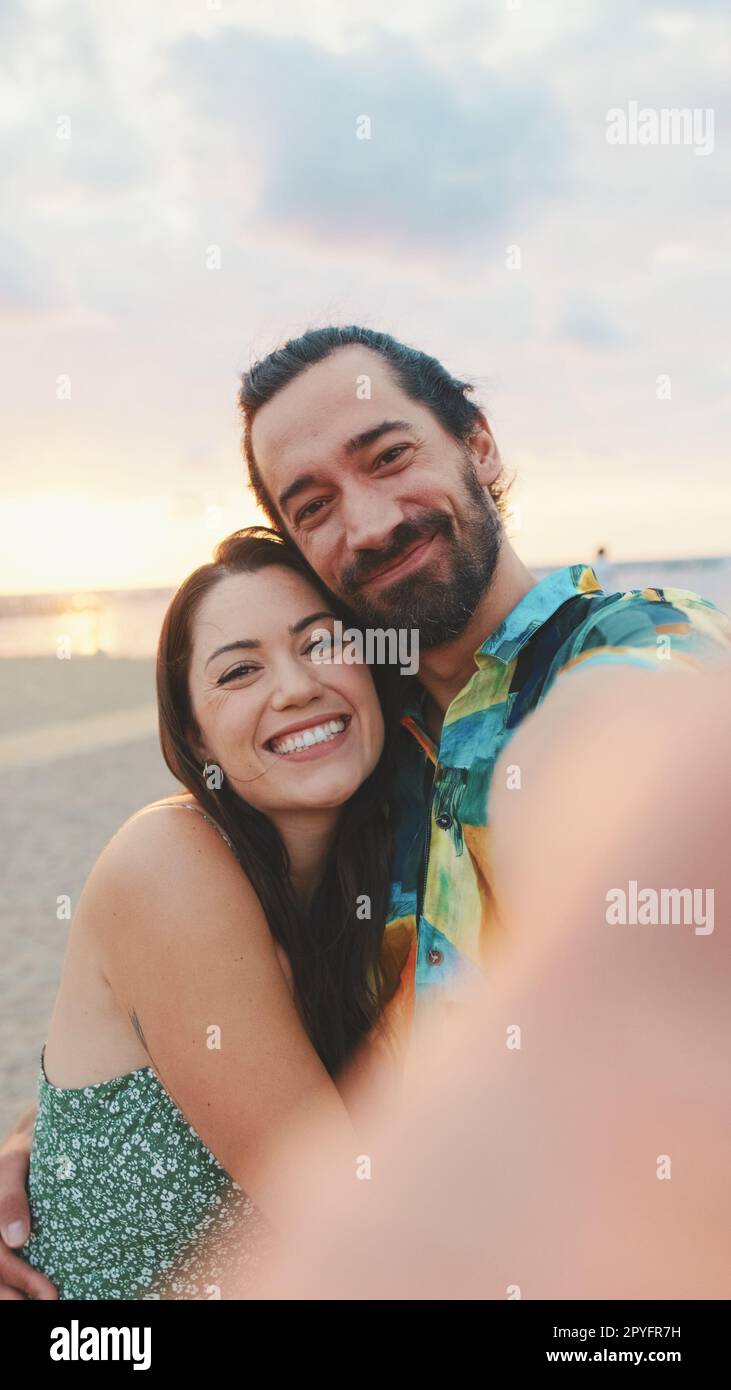 Laughing couple making video call while standing on the beach Stock ...