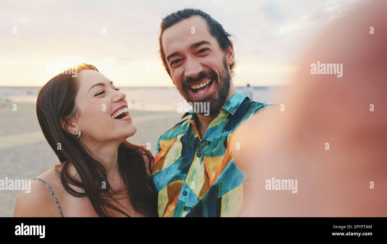 Laughing couple making video call while standing on the beach Stock ...