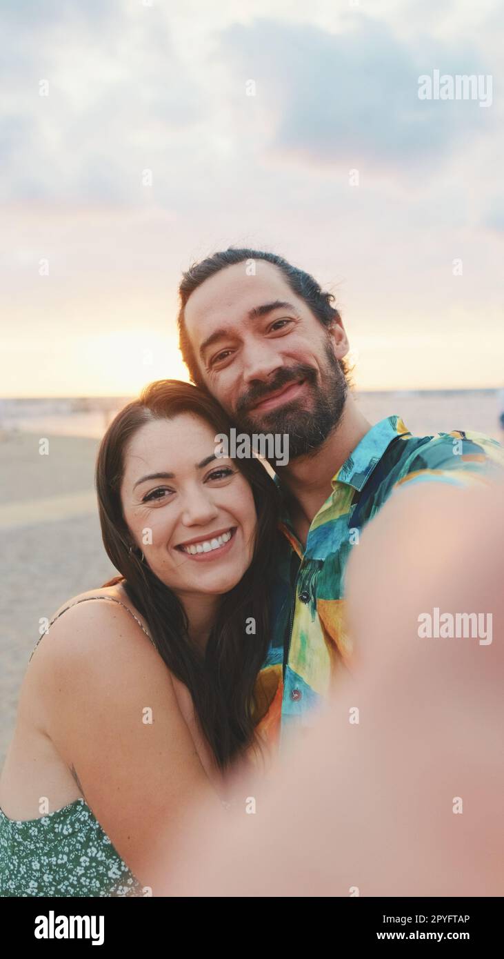 Laughing couple making video call while standing on the beach Stock ...