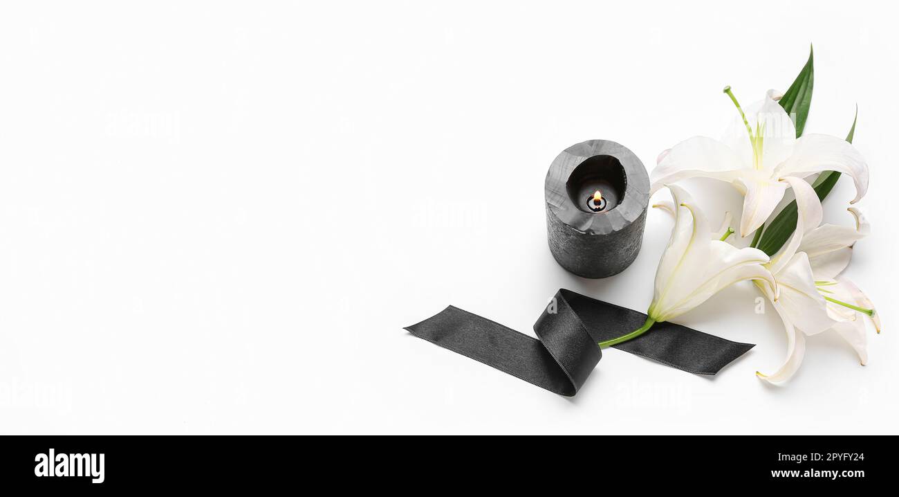 Lily flowers, black funeral ribbon and burning candle on white ...