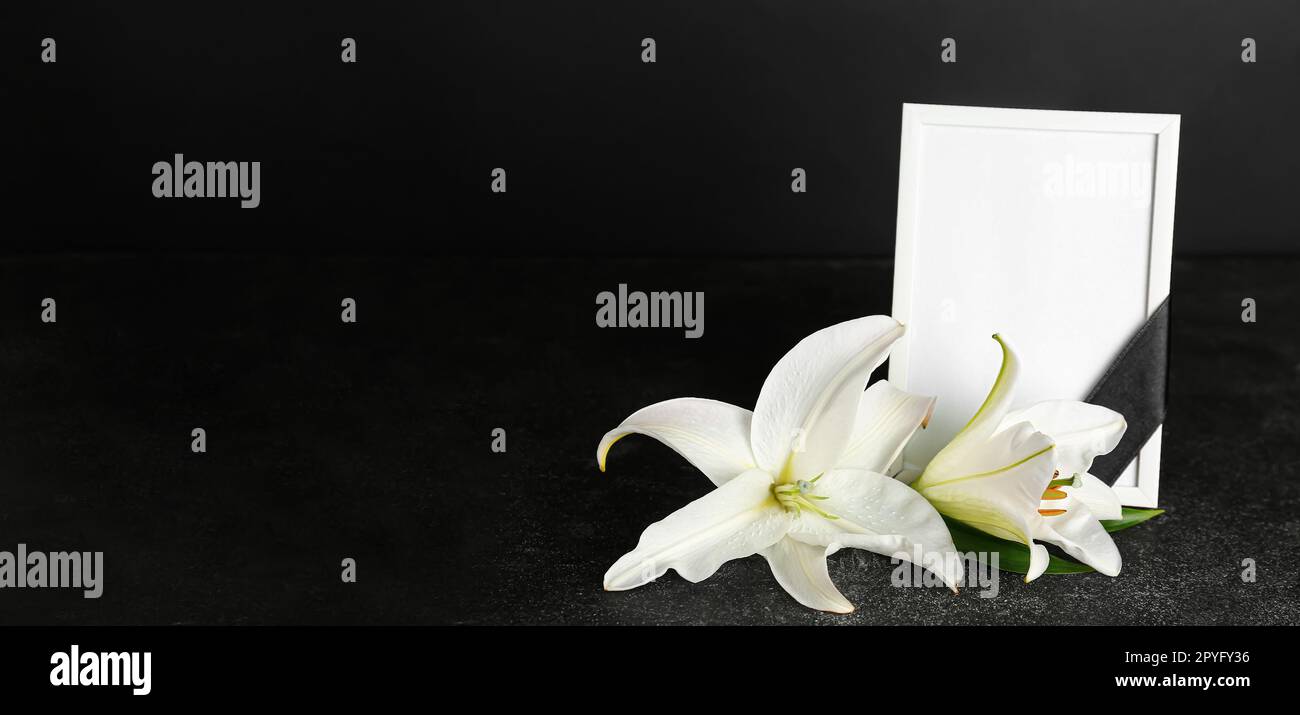Blank funeral frame and beautiful lily flowers on dark background with ...