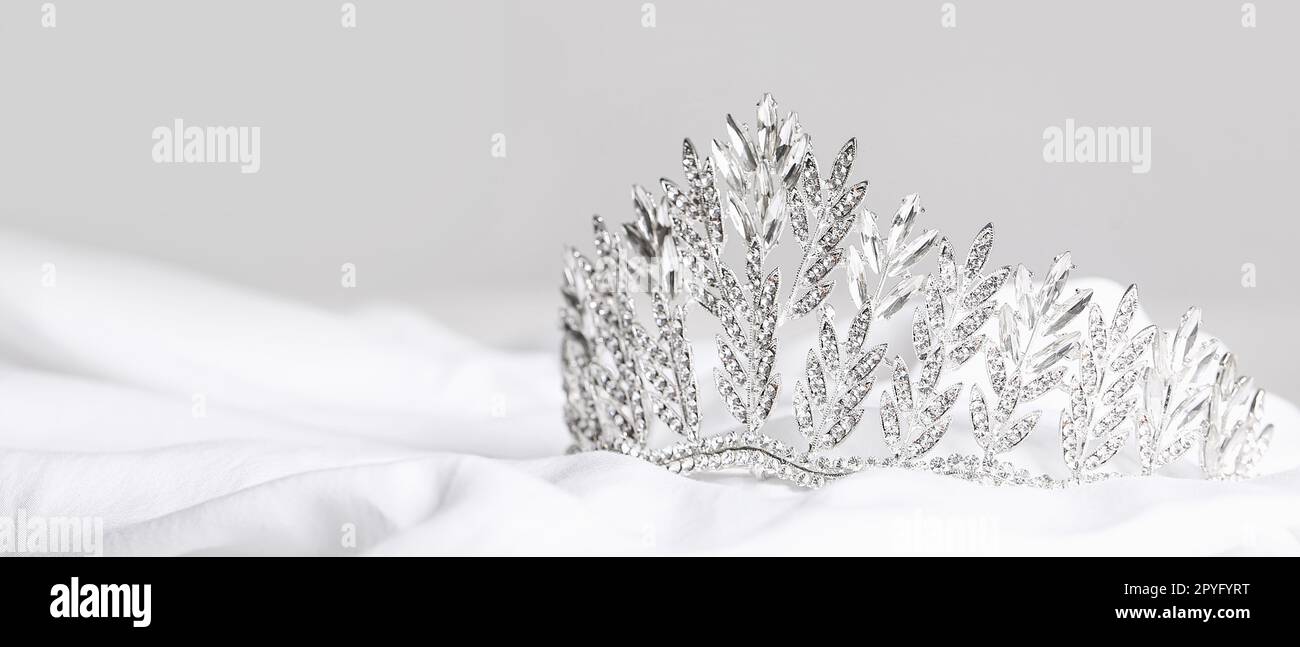 Beautiful tiara on white prom dress against grey background, closeup ...