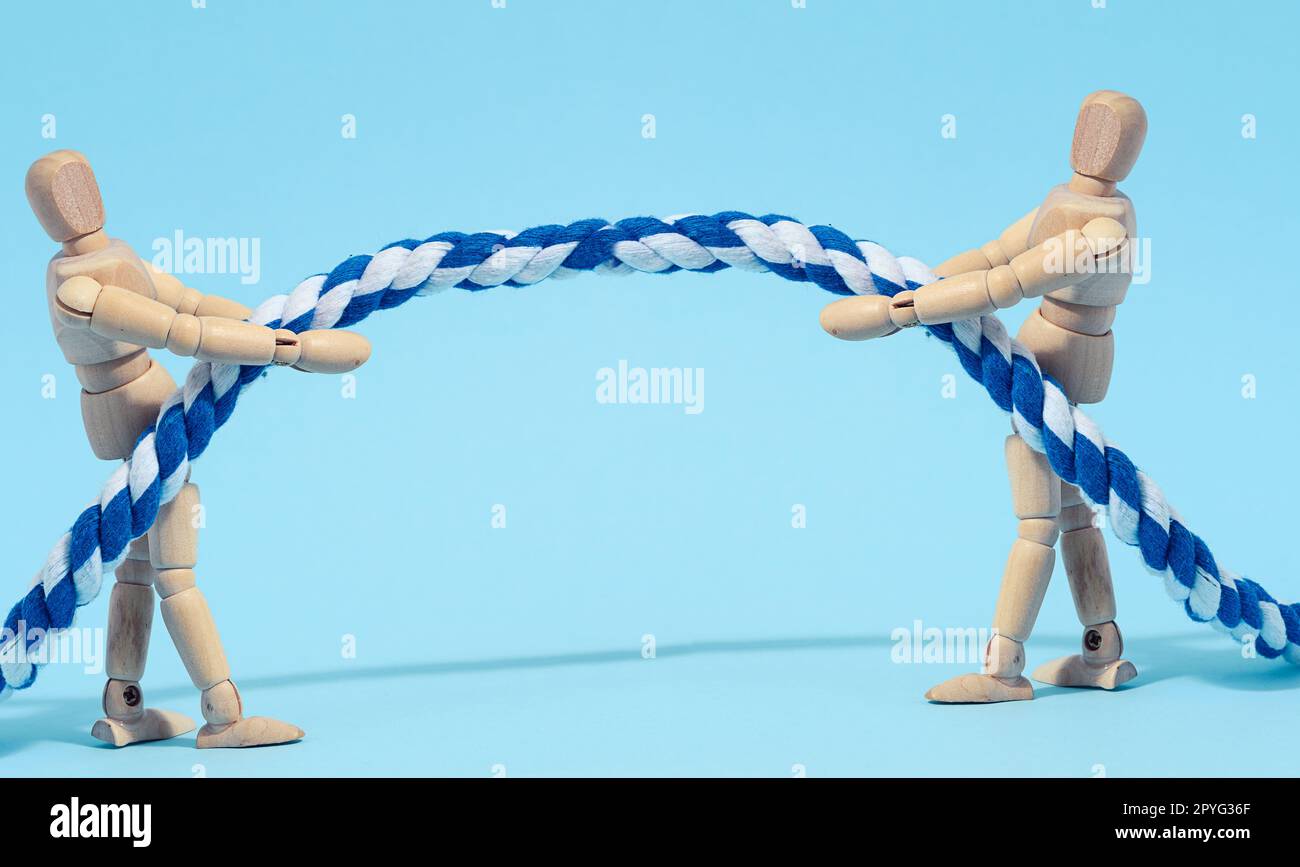 Two wooden mannequins are pulling a rope, concept of a strong leader in ...
