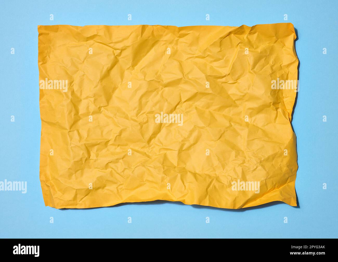 Yellow crumpled sheet of paper on a blue background, space for an ...