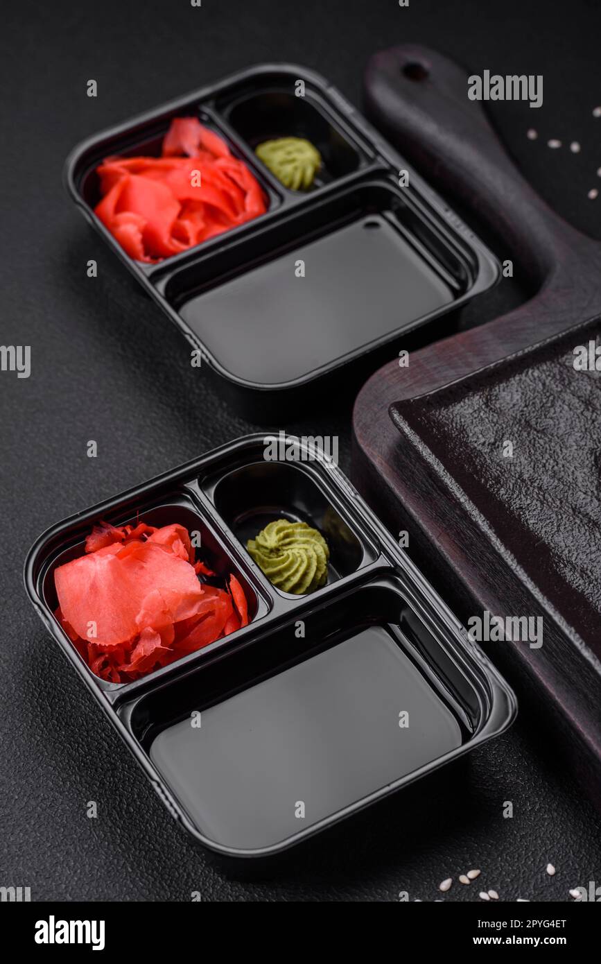 Pickled ginger, soy sauce and wasabi in portioned plastic containers on ...