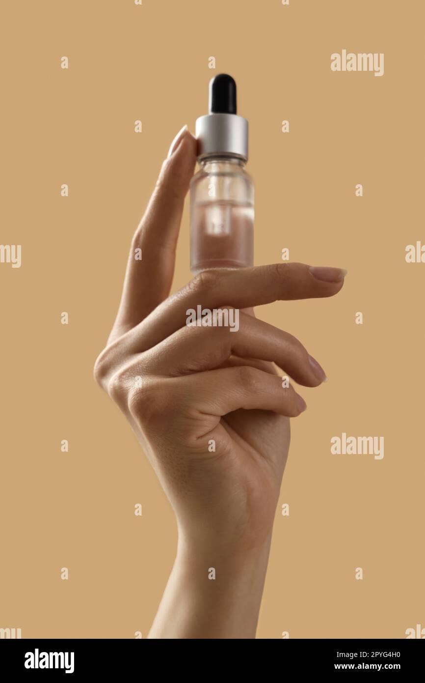 Hand holding cosmetic product on beige background Stock Photo - Alamy
