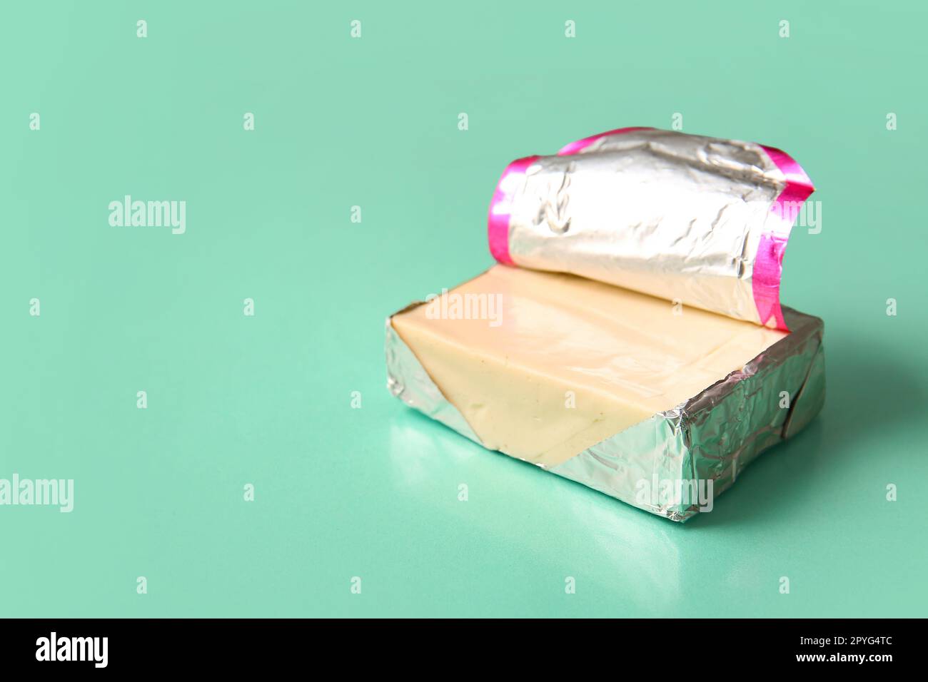 Processed cheese in foil on turquoise background Stock Photo - Alamy