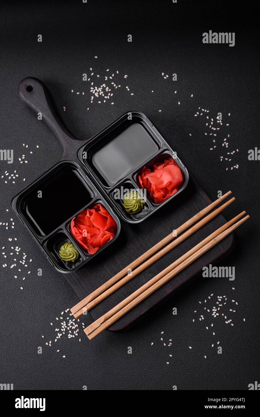 Pickled ginger, soy sauce and wasabi in portioned plastic containers on ...