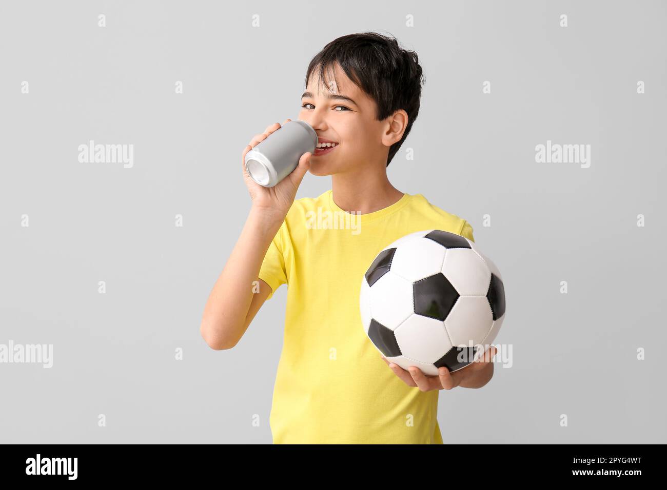 Little boy with soccer ball drinking soda on grey background Stock ...