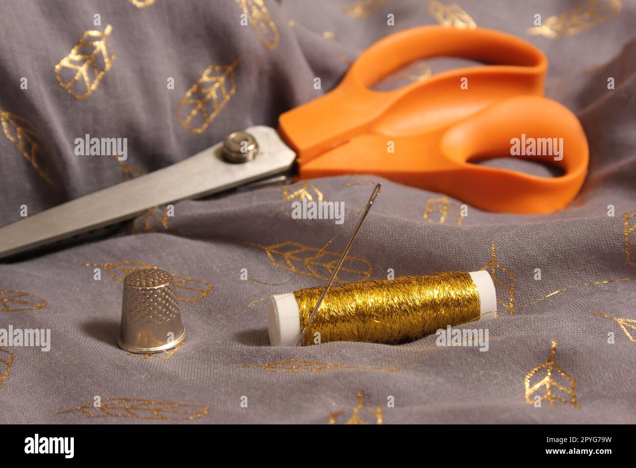 Spool of Metallic Gold Thread on Gray and Gold Fabric Stock Photo - Alamy