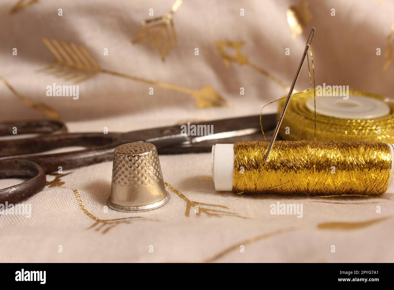Spool of Gold Thread and Scissors With Thimble on Metallic Fabric Stock ...