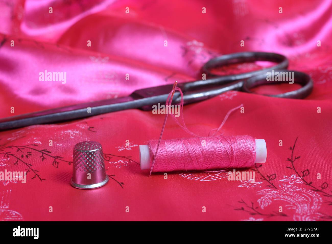 Spool of Pink Thread and Thimble on Vintage Pink Satin Fabric Stock ...