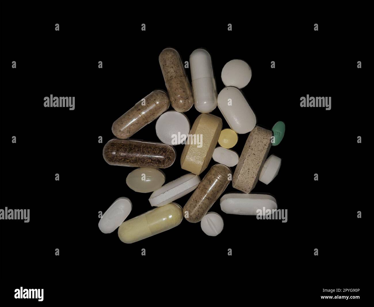Many assorted pills jumbled together on a white surface - a combination ...