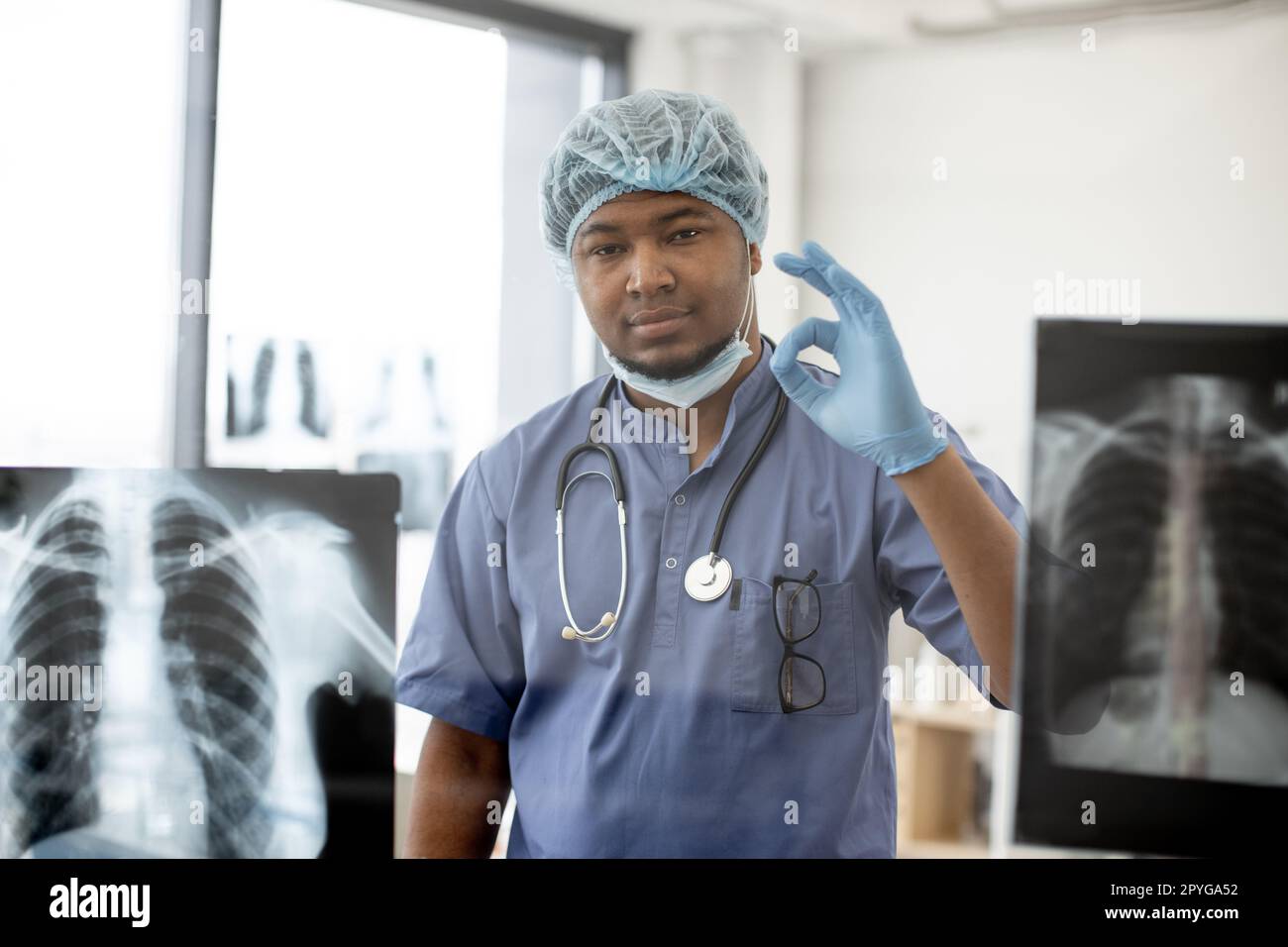 Friendly multiracial male in scrub top and latex gloves giving sign ok ...