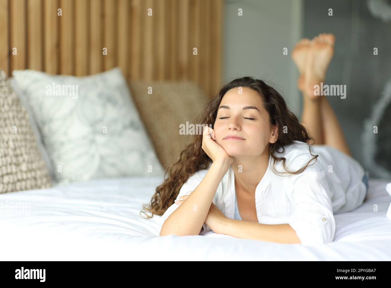Happy woman lying on bed relaxing Stock Photo - Alamy