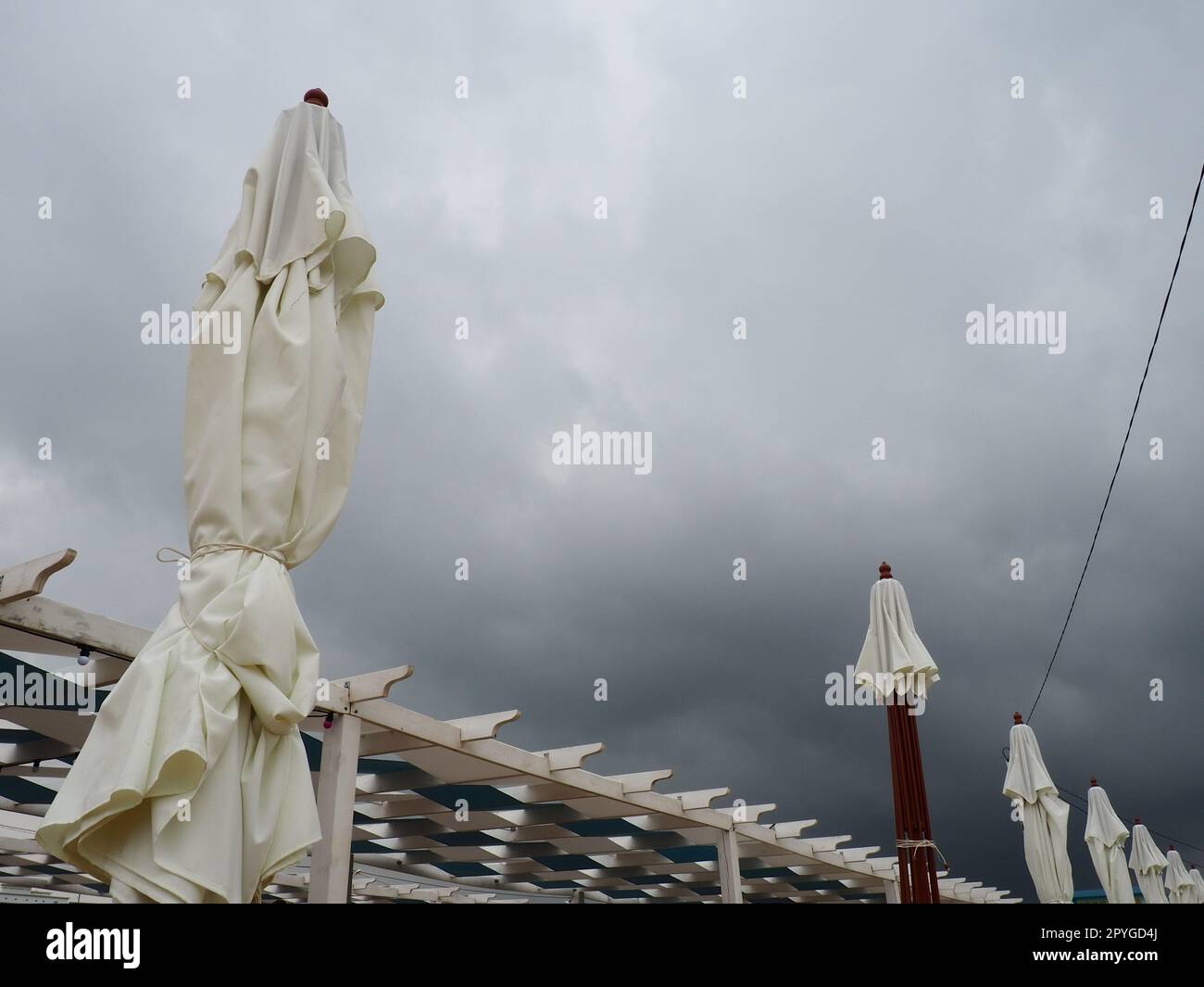 Wet sunbeds and umbrellas on the sea beach during heavy rain storm ...