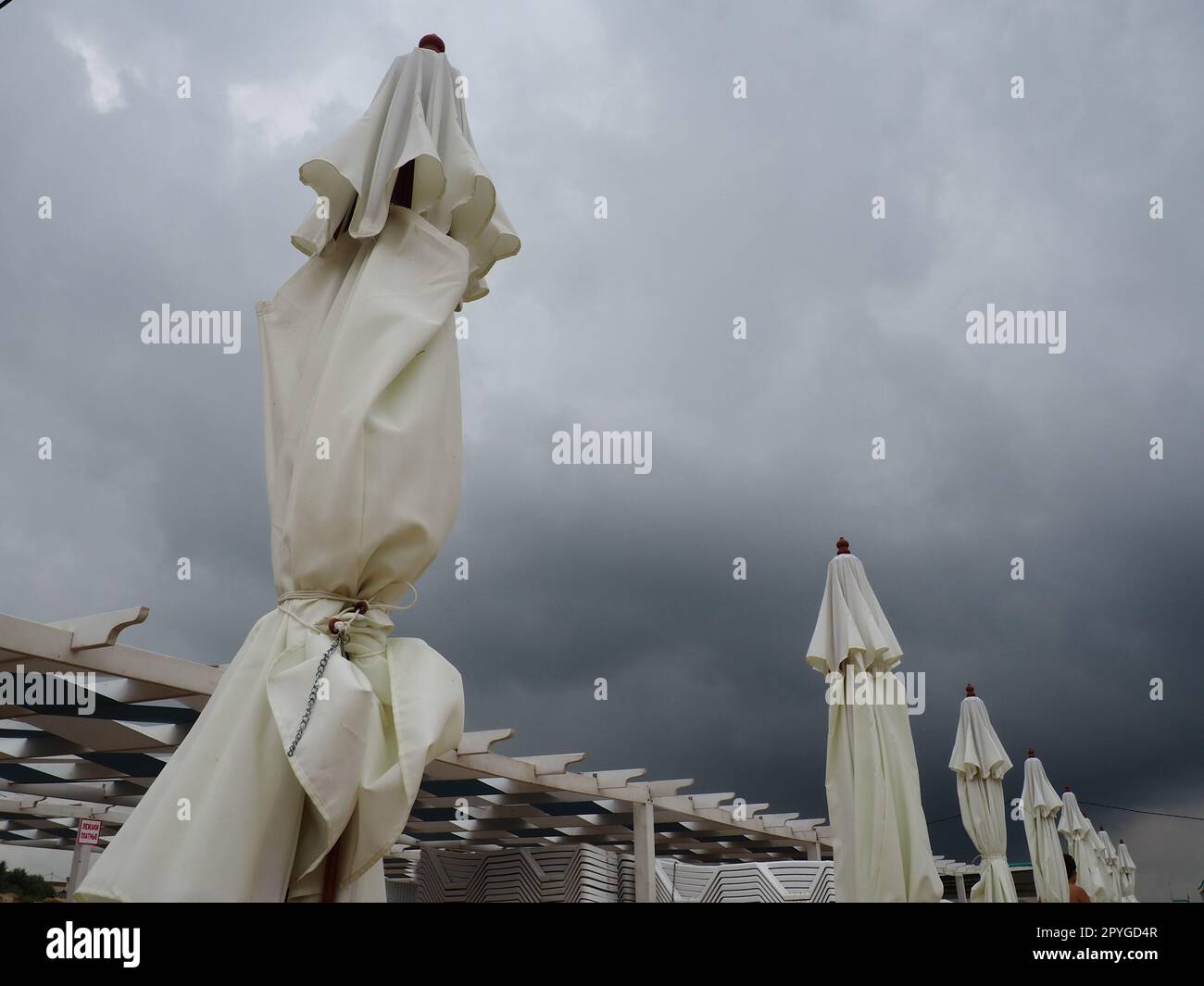 Wet sunbeds and umbrellas on the sea beach during heavy rain storm ...