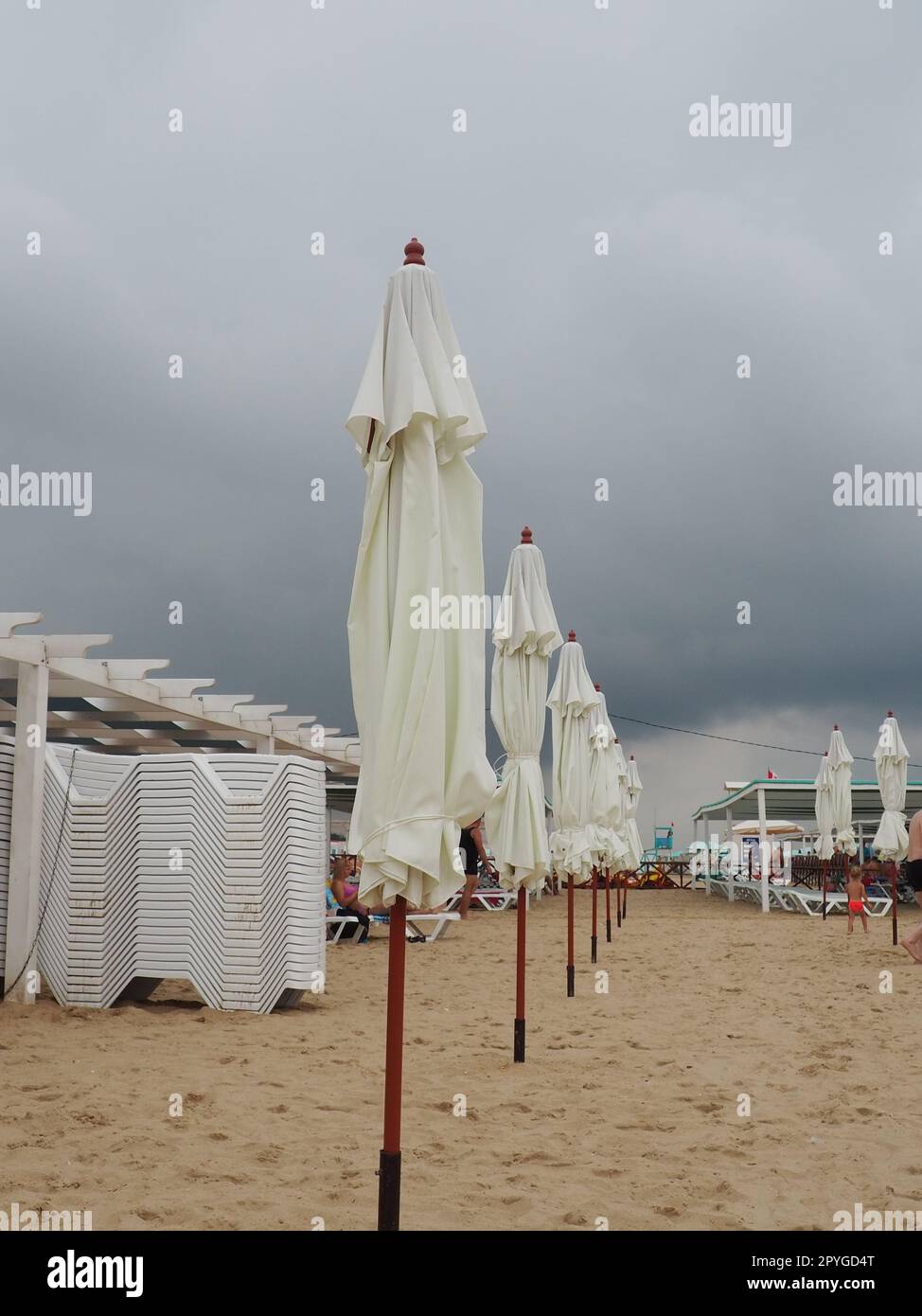 Wet sunbeds and umbrellas on the sea beach during heavy rain storm ...