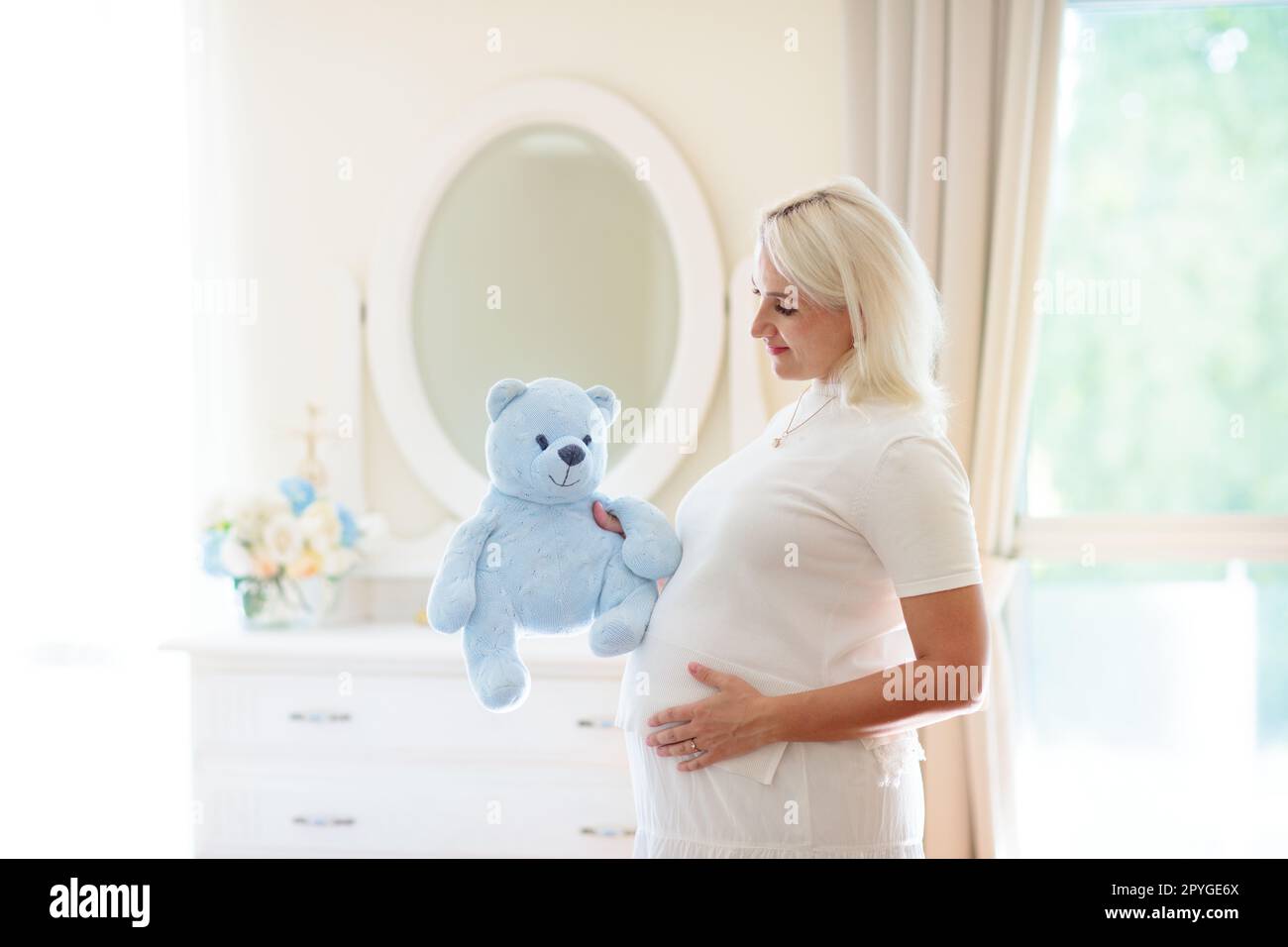 Pregnant woman at home. Young expecting mother in white bedroom with ...