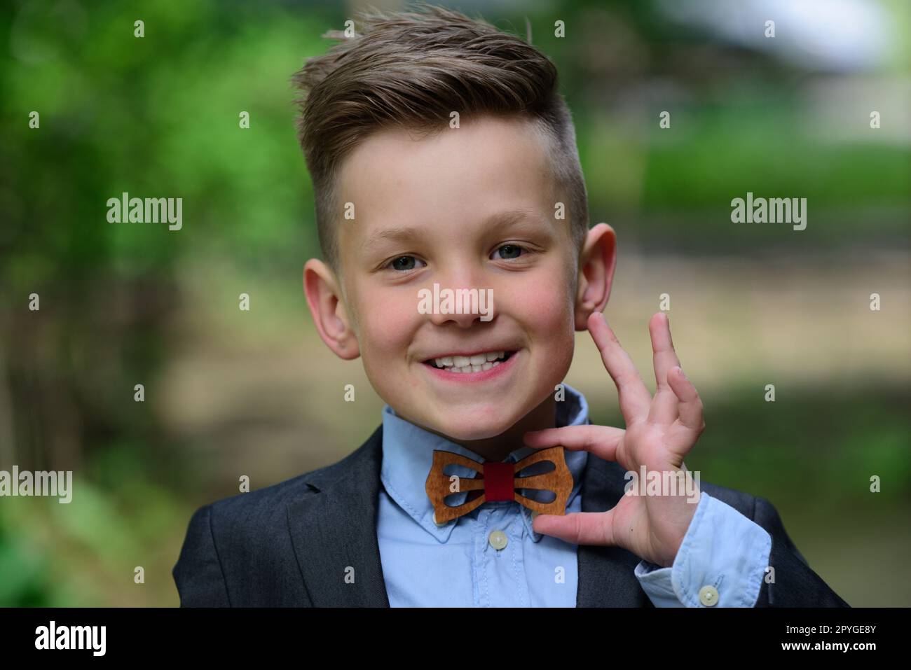 Little fashion portrait of kid boy in suit and bow tie. Outdoor closeup ...