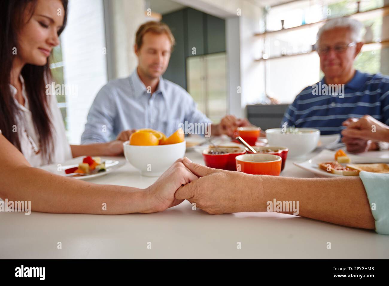 Eat, pray, love. a family saying a prayer before eating their food ...