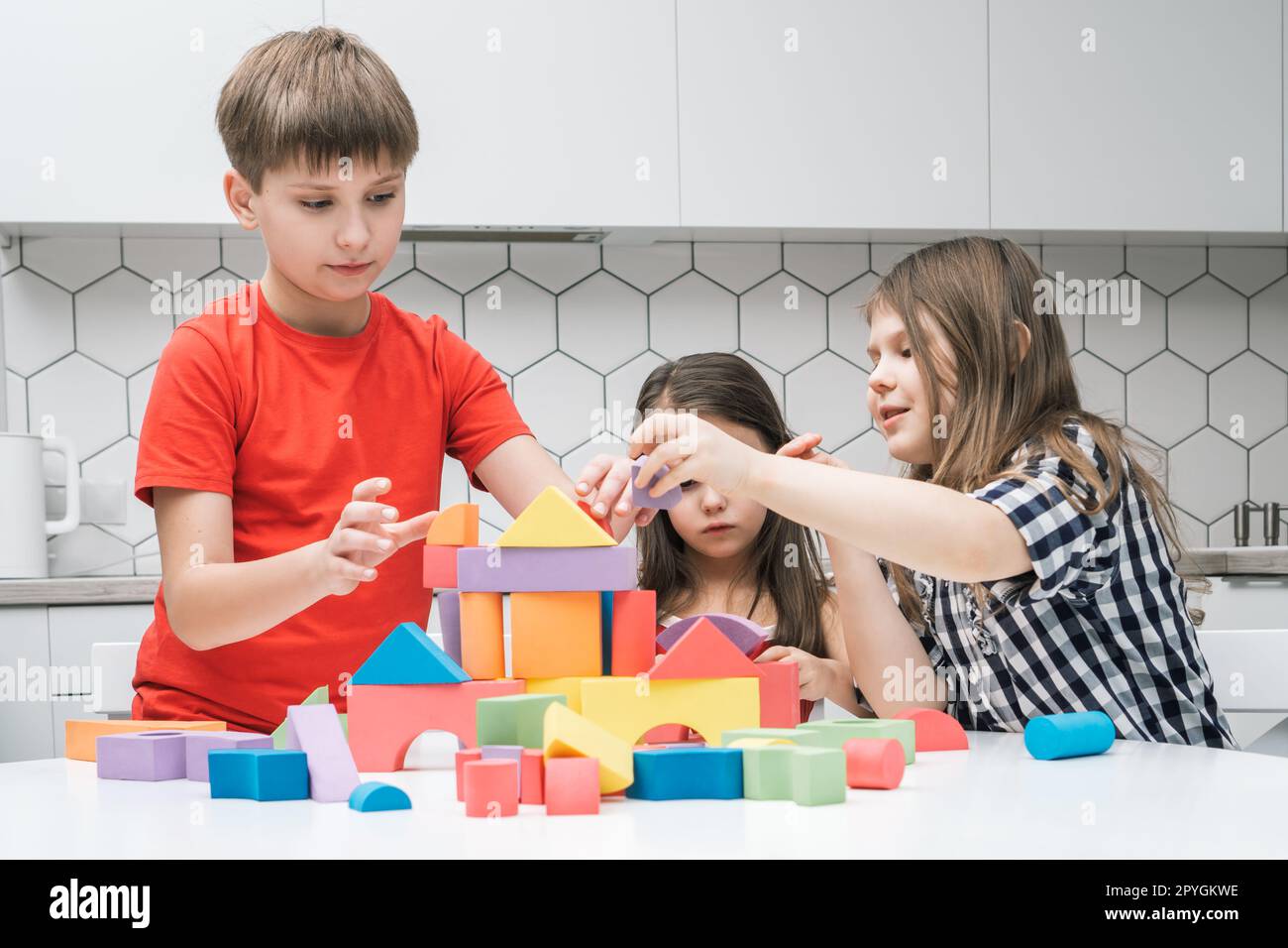 Positive, focused children of boy and two girls playing with colorful ...