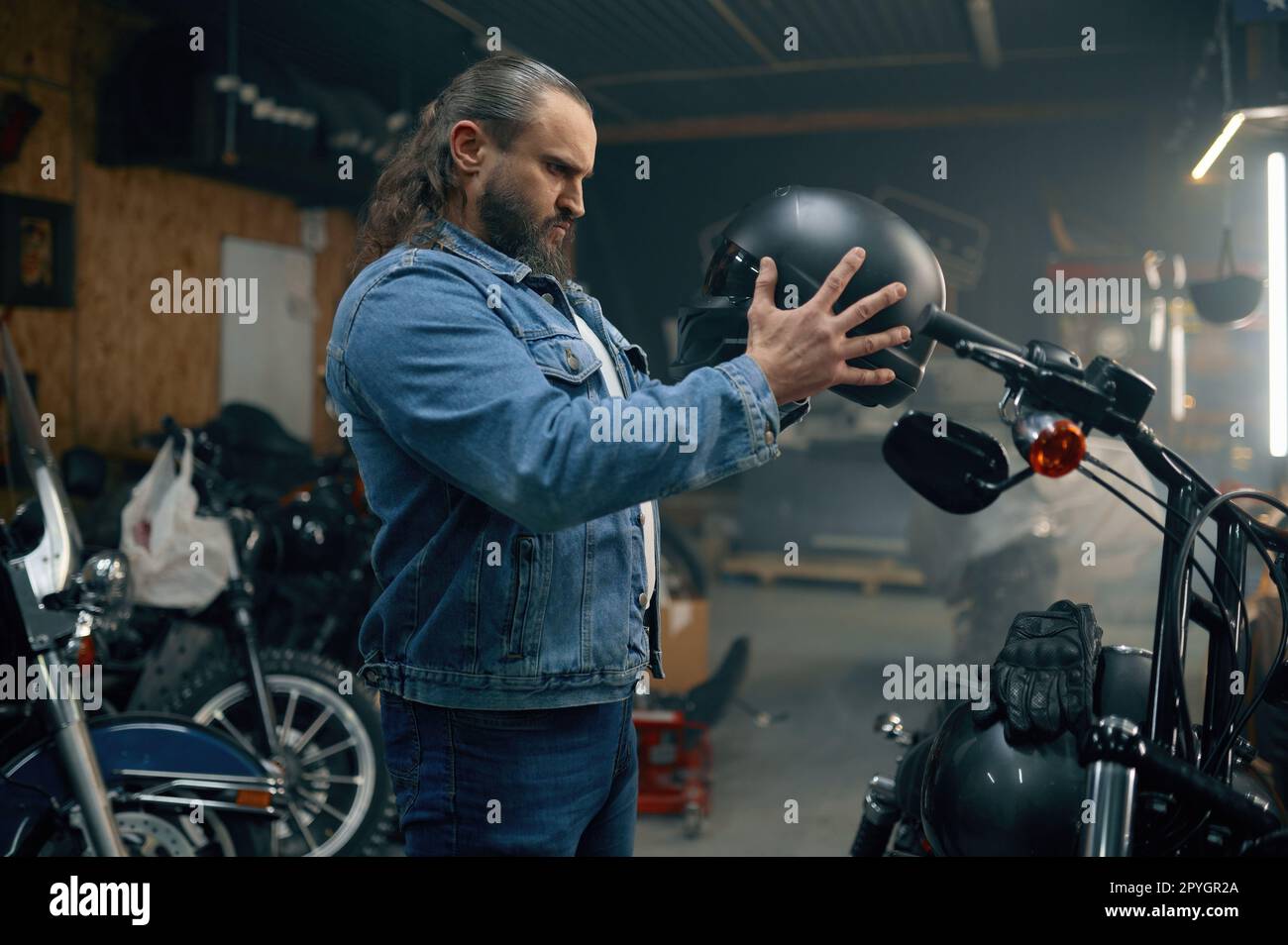 Side view shot on biker choosing new modern safety helmet in motorcycle ...