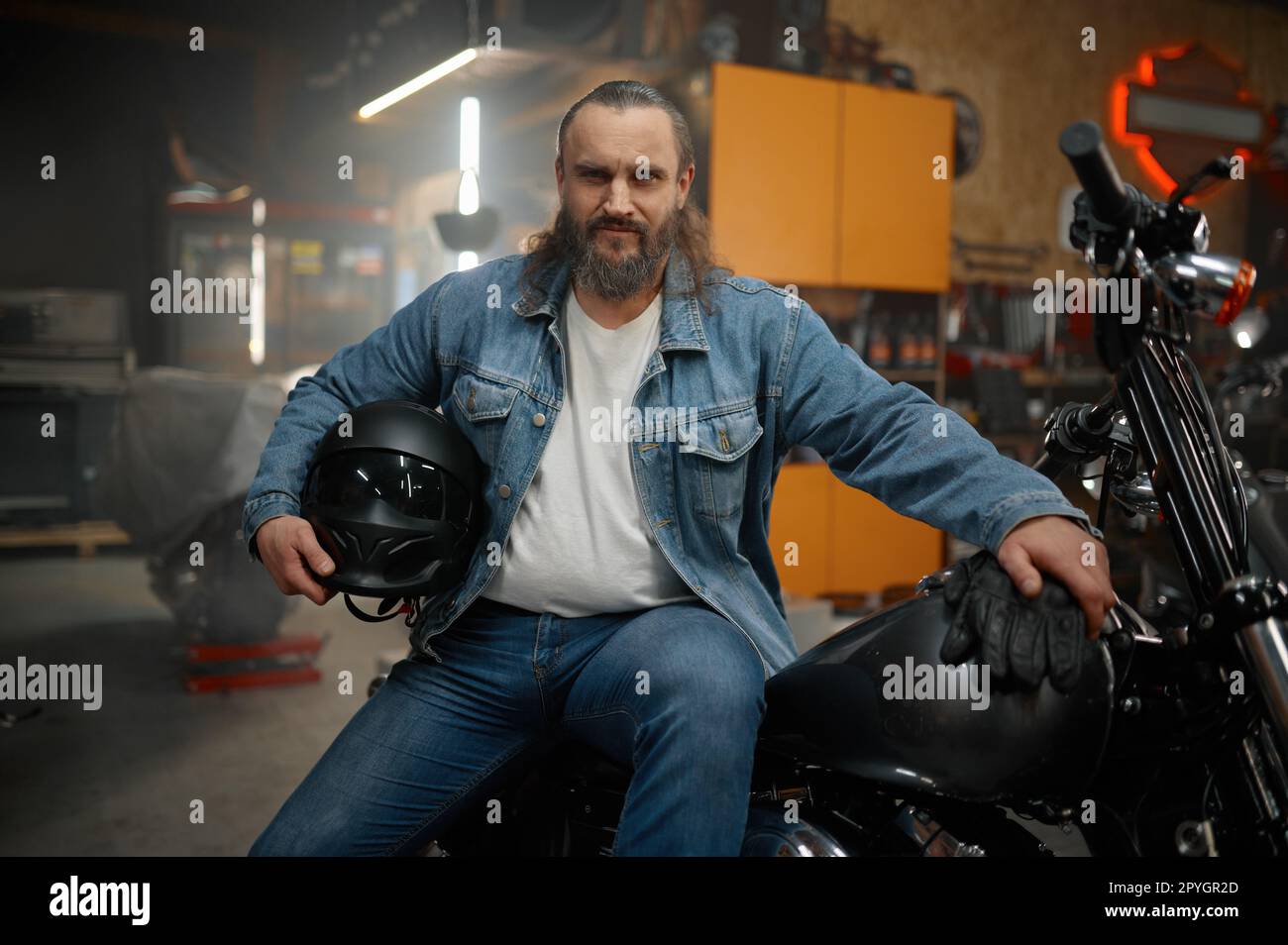 Portrait of smiling biker on new motorcycle holding modern safety ...