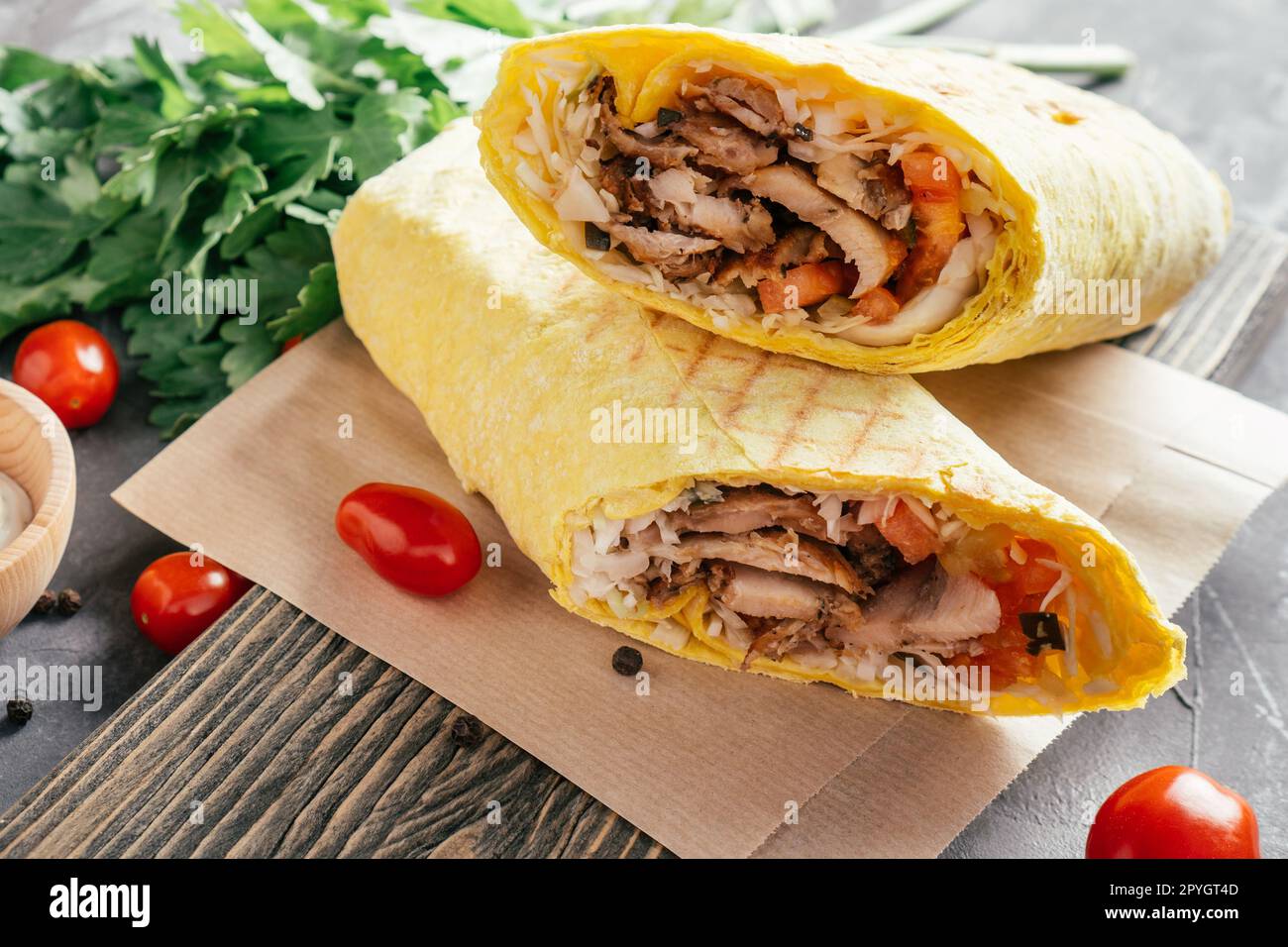 Classic shawarma with chicken and vegetables in pita bread on wooden ...