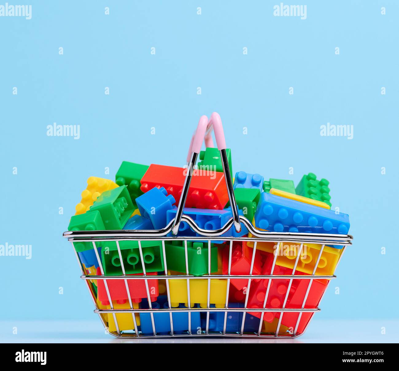Plastic colorful building blocks in a miniature metal shopping cart ...