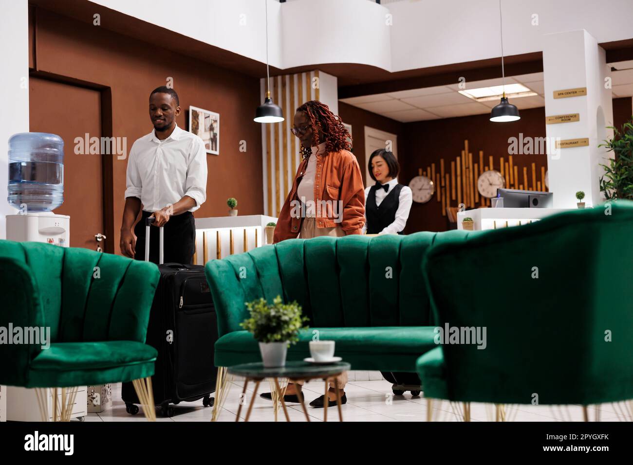 Couple sitting in lounge area at hotel, waiting to register and do ...