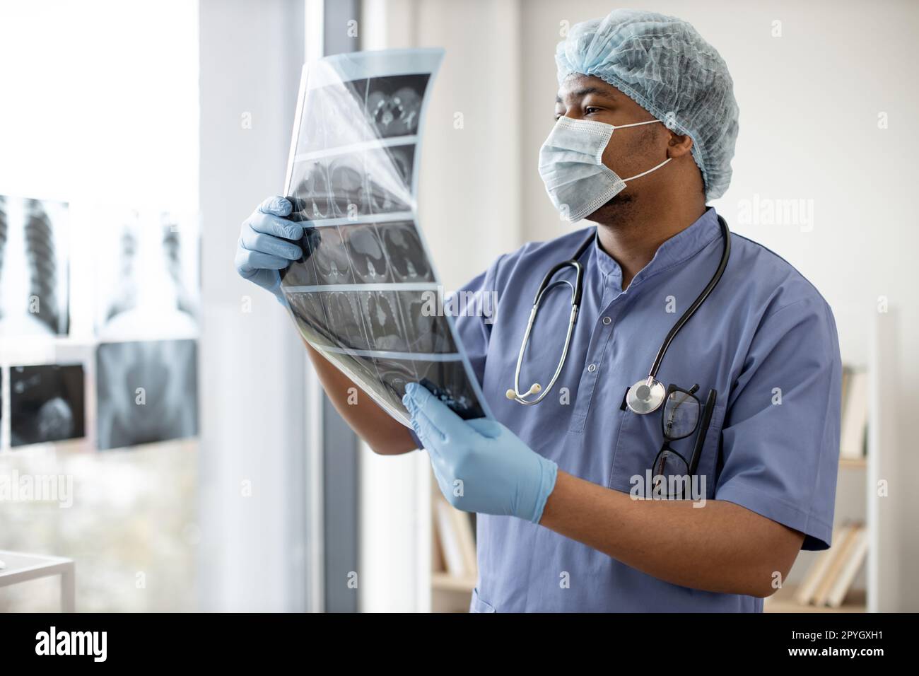 Mindful multiethnic man in protective garment holding detailed CT scan ...