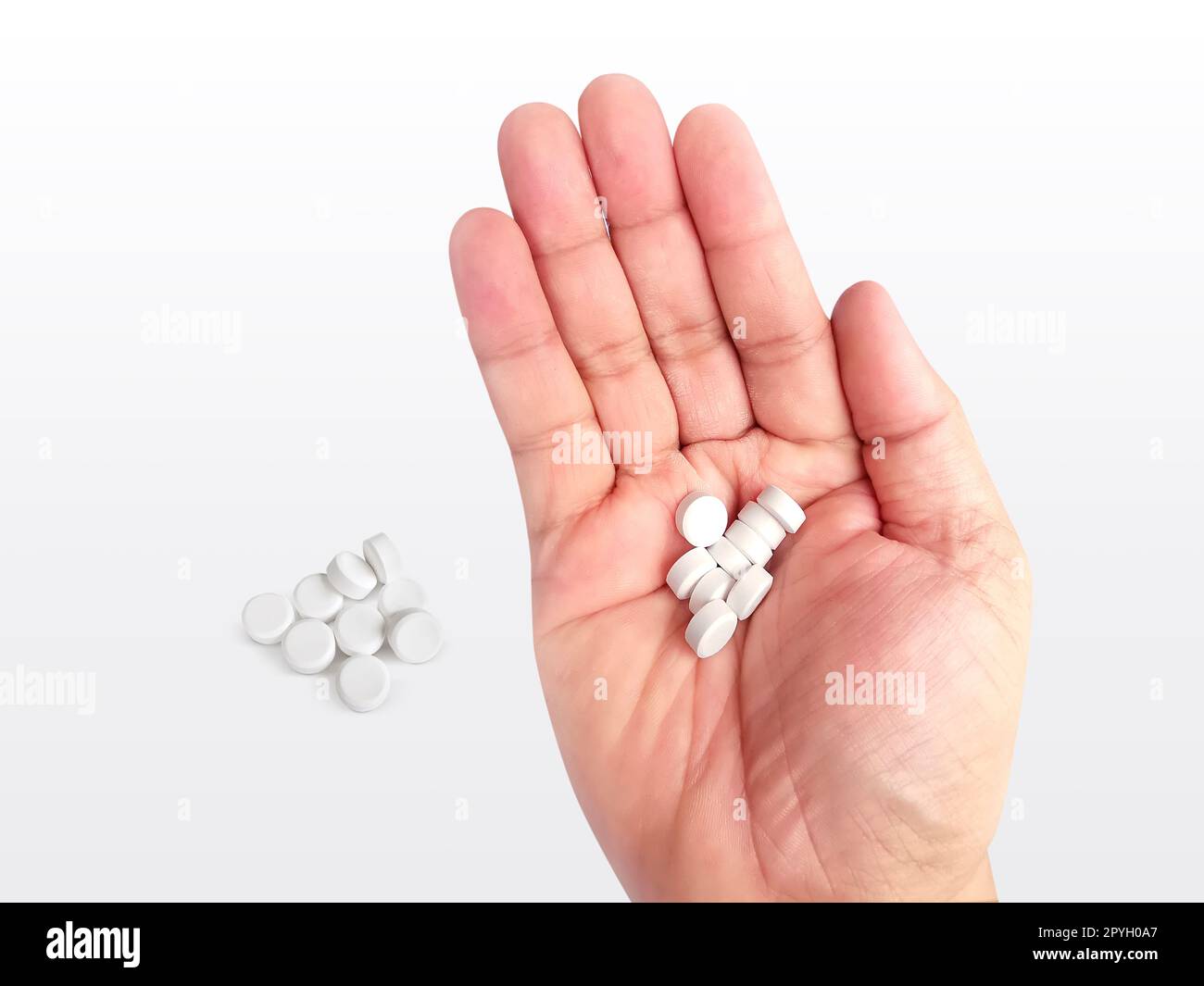 A handful of white pills in hand on a white background Stock Photo - Alamy