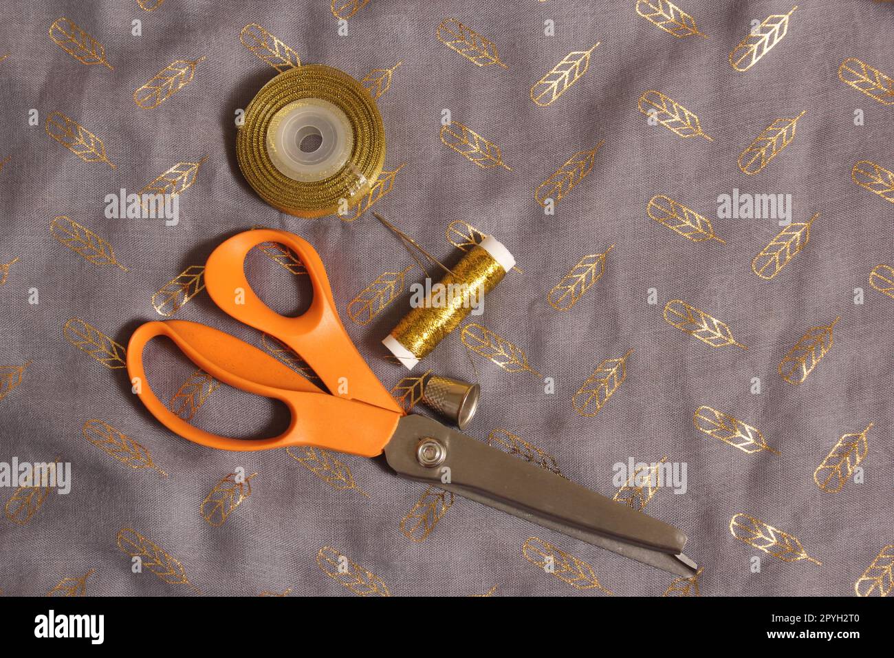 Spool of Metallic Gold Thread on Gray and Gold Chiffon Fabric Stock ...