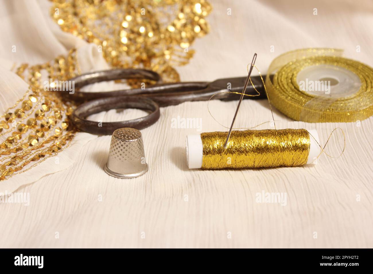 Spool of Gold Thread and Scissors With Thimble on Off White Fabric With ...