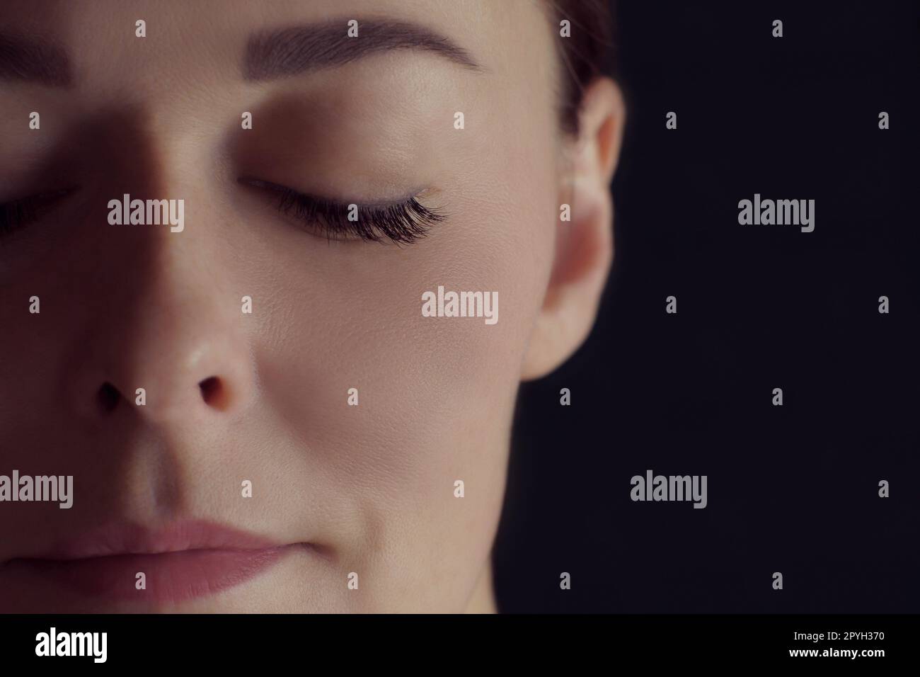 Close-up of half-face of pretty young woman with closed eyes with ...