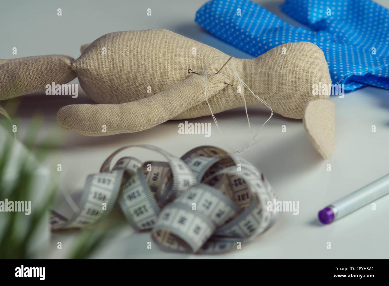 Sewing create of stuffed rabbit toy with needle in body lying on table ...