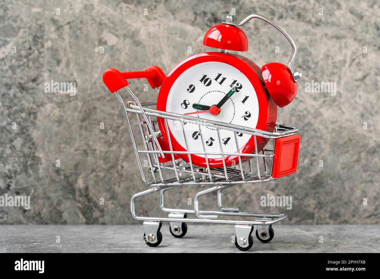A metal supermarket trolley with alarm clock inside Stock Photo - Alamy