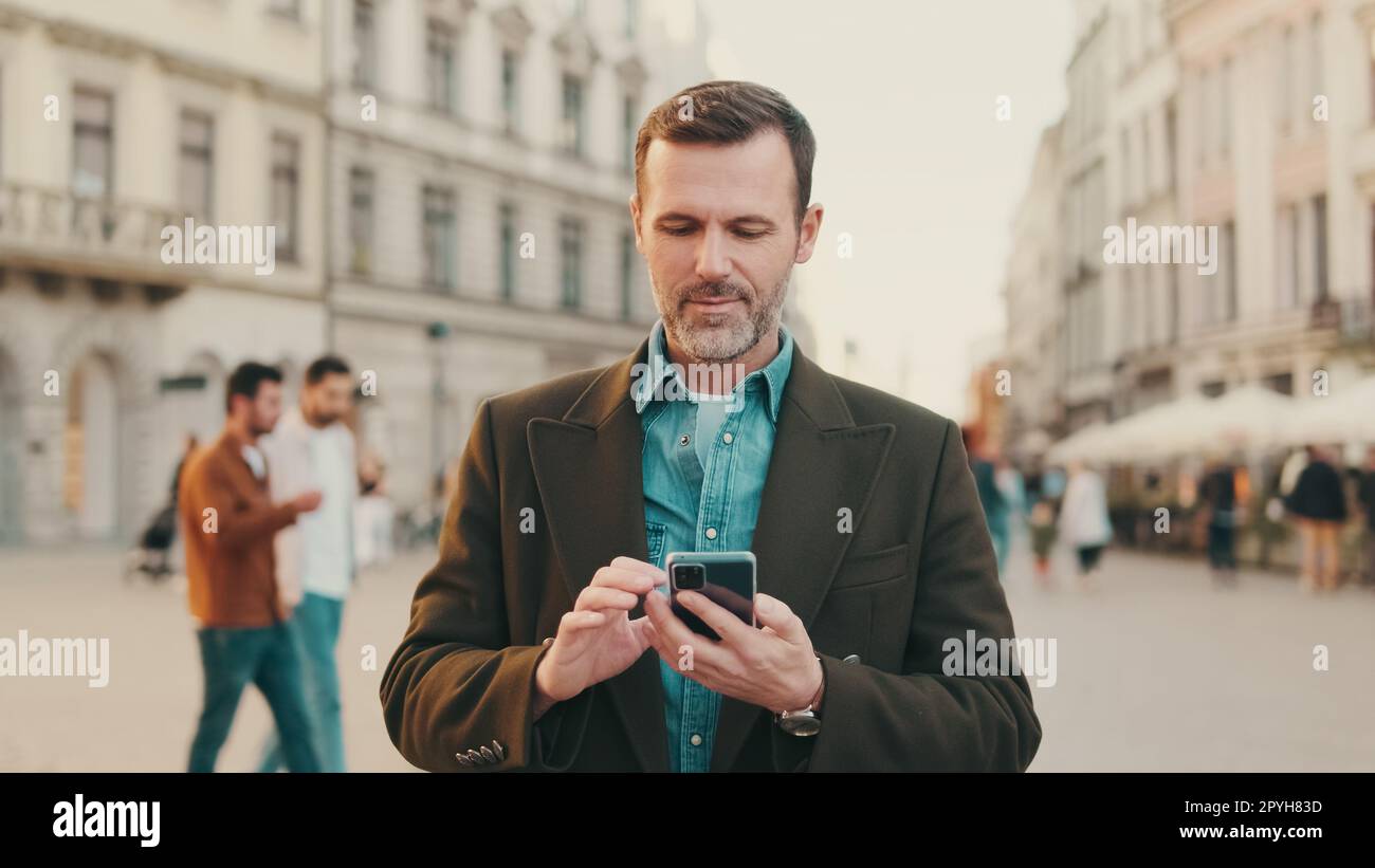 Middle aged man using map app on mobile phone on the old town ...