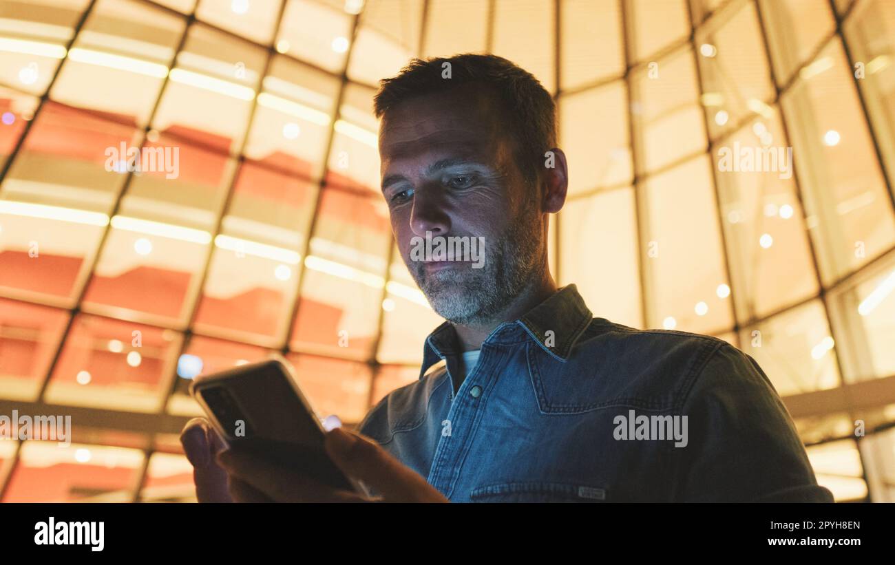 Close up, middle-aged man uses mobile phone in the evening standing ...