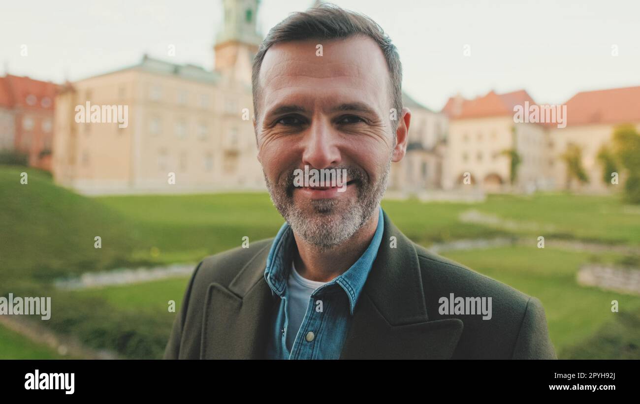 Close up, man looks at the camera and smiles at the old city background ...
