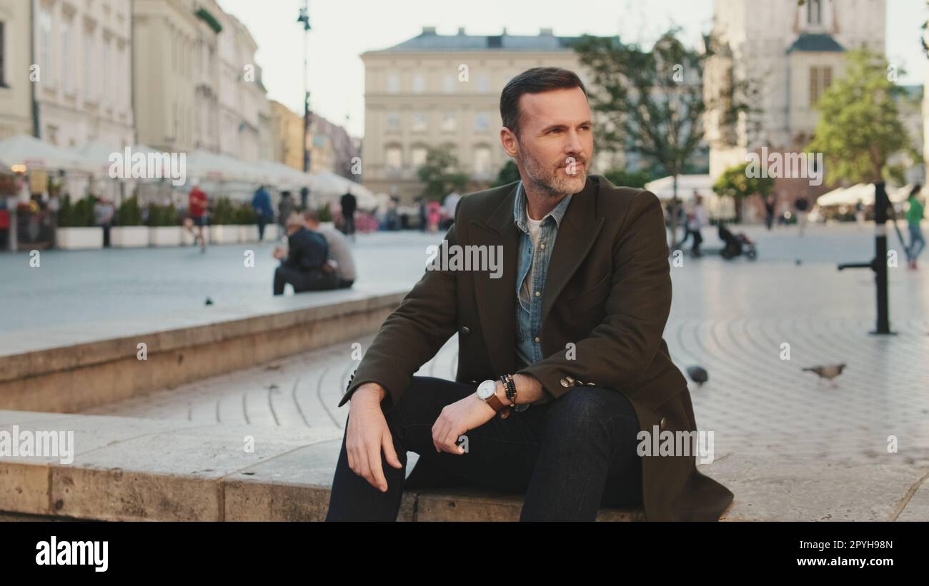 Bearded man sitting on the square of the old town Stock Photo - Alamy