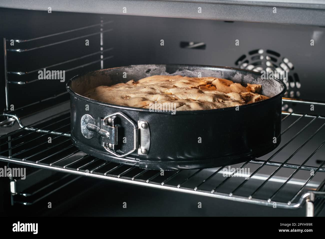 Baking dish with apple pie stands in black oven. Homemade seasonal ...