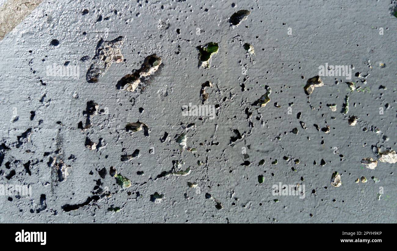 Concrete wall with concentric damage of large radius. Potholes ...