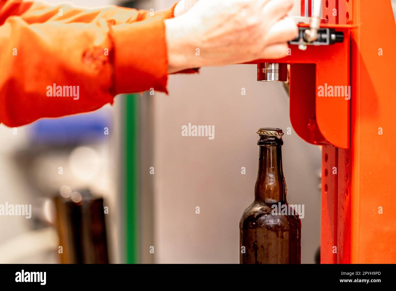 mechanical capping of beer bottles in the brewery Stock Photo - Alamy